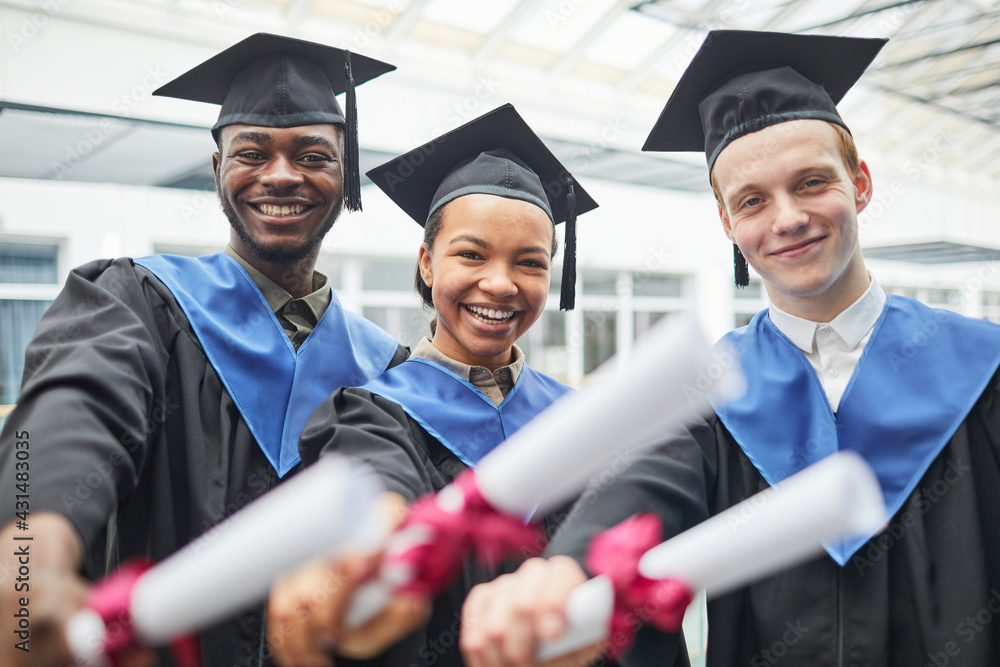 Diverse group of college graduates holding diploma certificates and ...