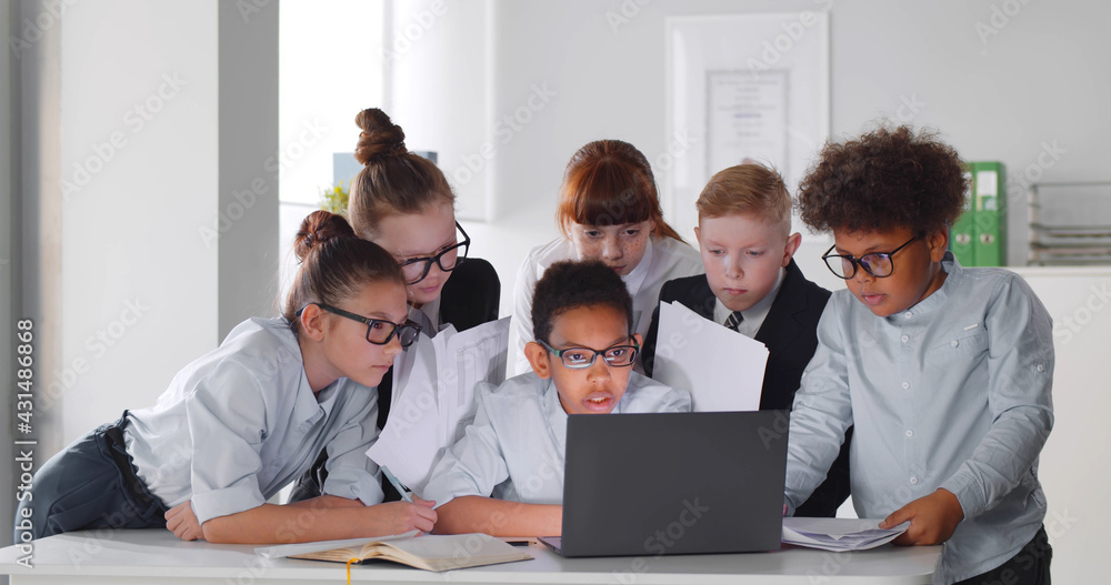 Kids office colleagues looking at laptop discussing work together in ...
