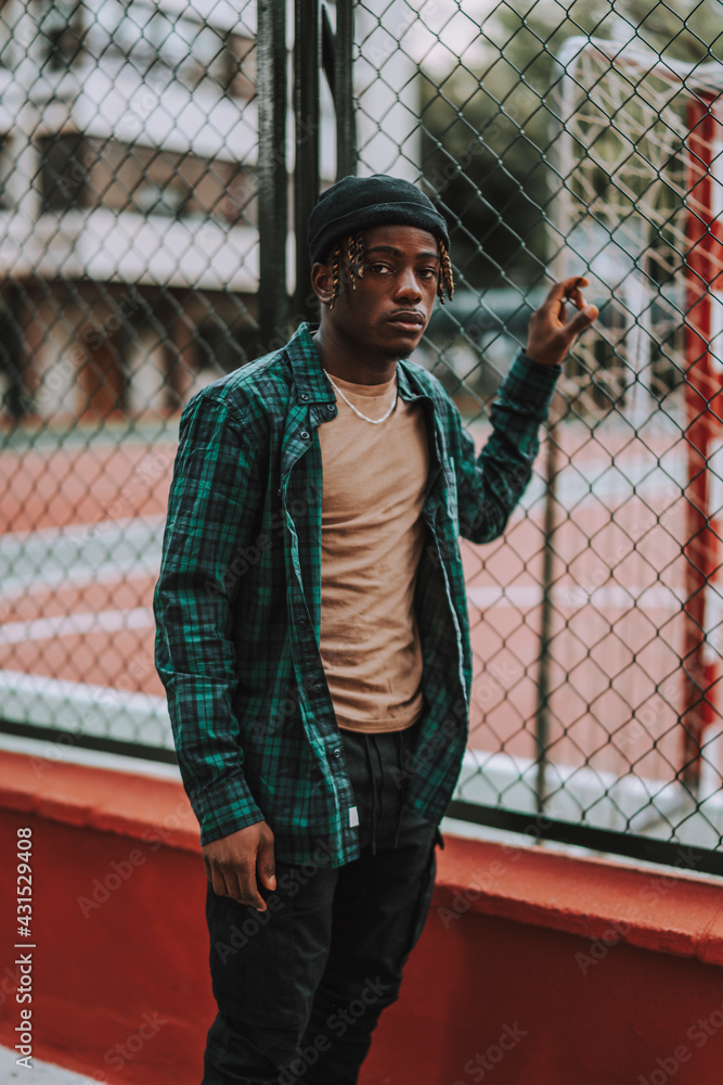 Chico negro joven y guapo posando junto a una cancha de baloncesto ...