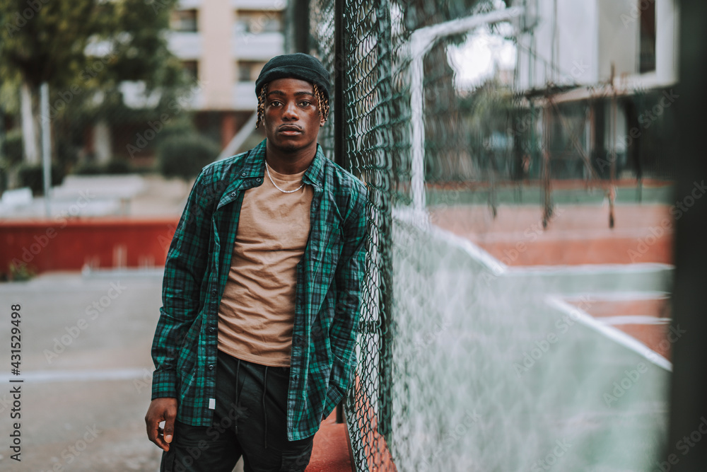 Chico negro joven y guapo posando junto a una cancha de baloncesto ...