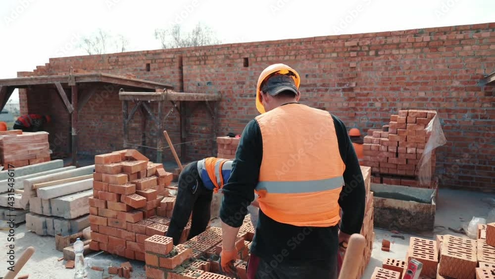 Builders building a brick wall. Construction work on construction. The ...