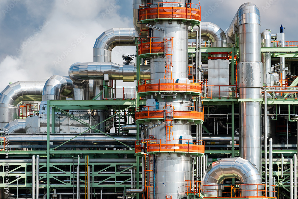 Industrial distillation tower and metal pipes at a chemical plant ...