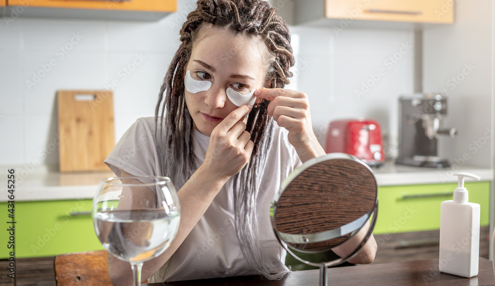 Young woman with dreadlocks on her head puts a mask on her face for the ...