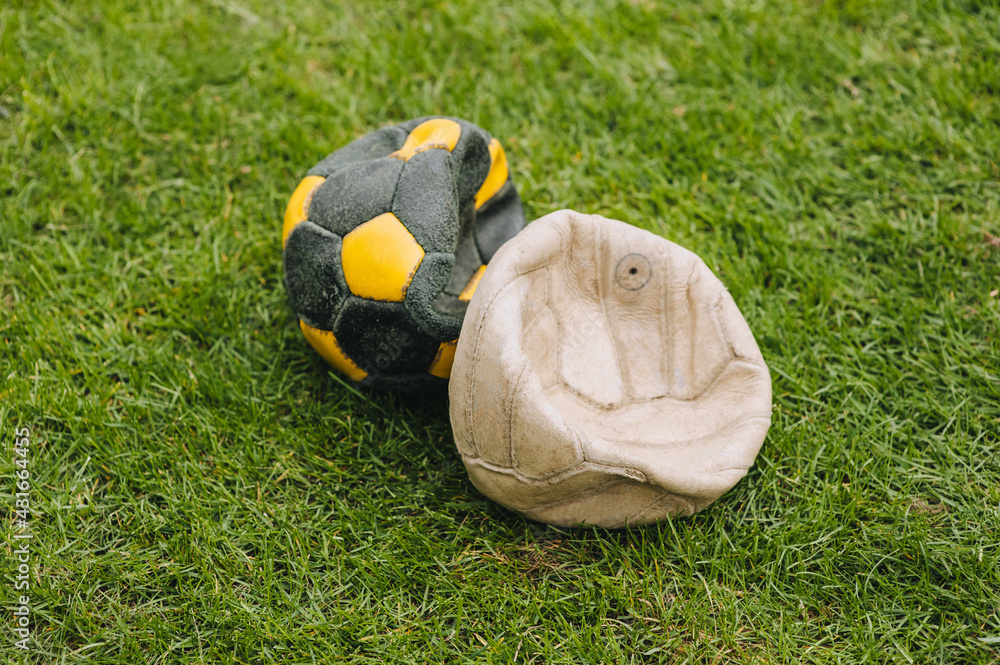 A pair of deflated football old multi-colored balls lie on the green ...