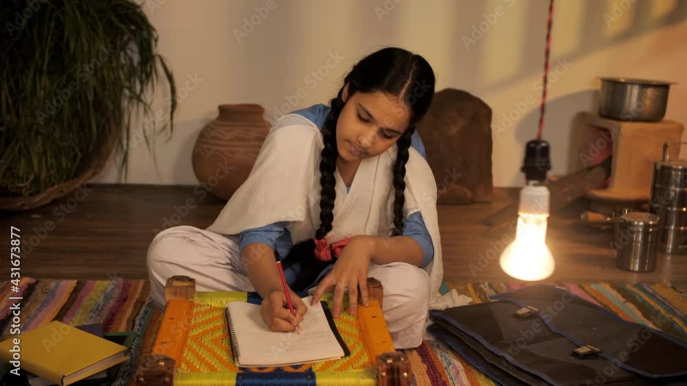 A teenage girl wearing a school uniform studying in the light of an ...