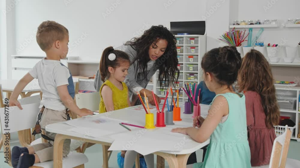 Young teacher talking with the kids while they are drawing. Stock Video ...