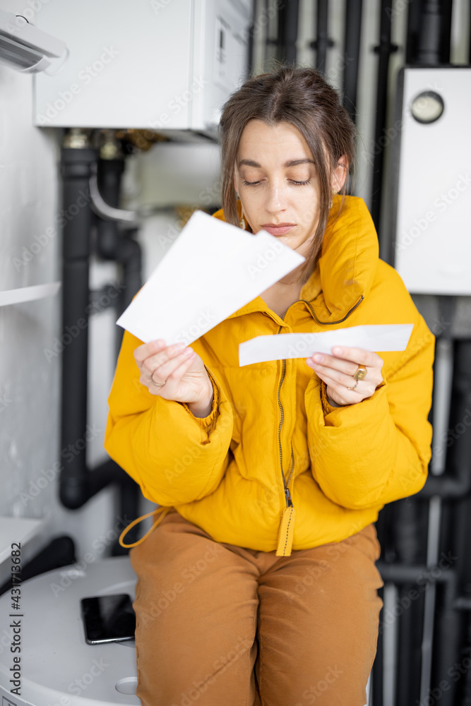 Confused woman looks at electricity bills, comparing data with the ...