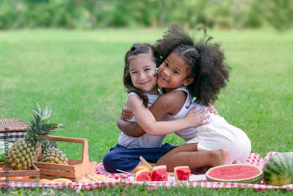 Two child girl of different ethnicities hugging each other on a picnic ...