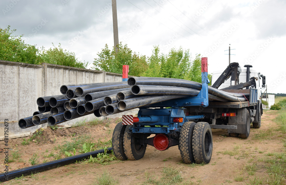 Plastic water pipes are stacked in a pile on a large truck, ready to be ...
