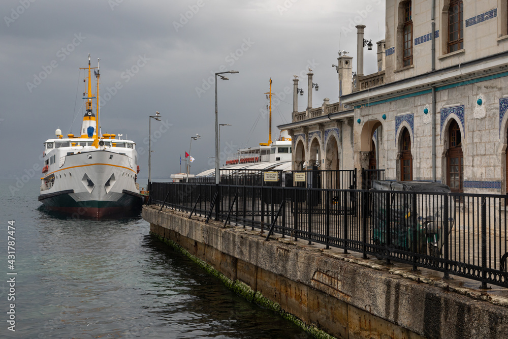 A passenger transport ferry is moored in the distance at a concrete ...
