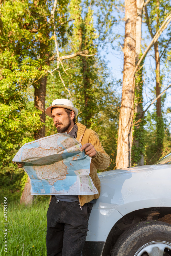 Fotka „Latino man leaning on his 4wd suv car consulting on a map the ...