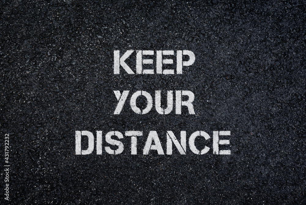 "Keep your distance" sign/text on dark, wet asphalt road, top view ...