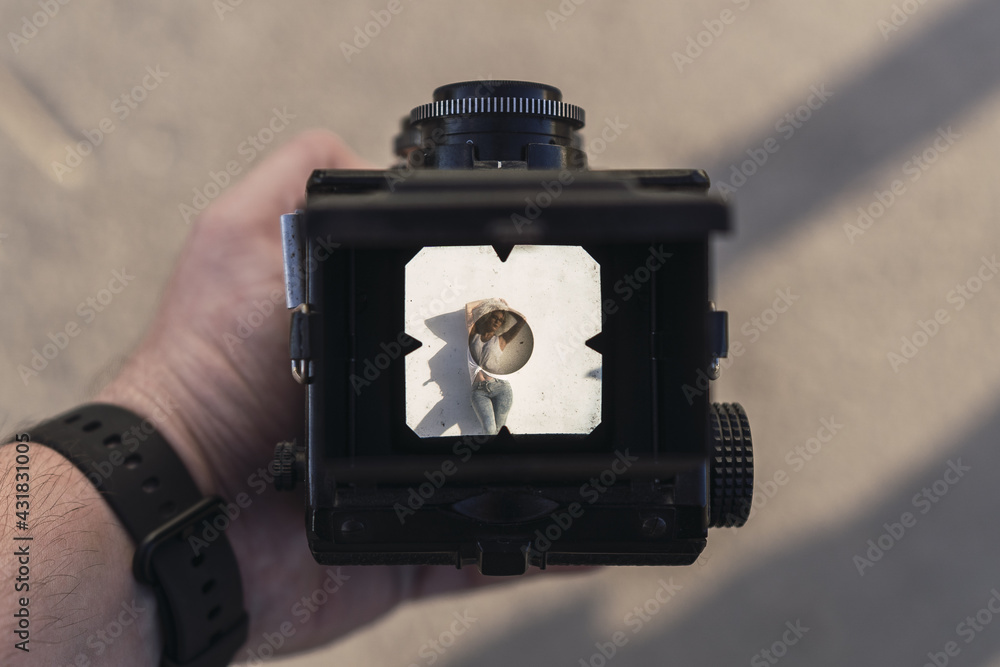 Male hand holding TLR lens of an old medium format camera with a girl ...