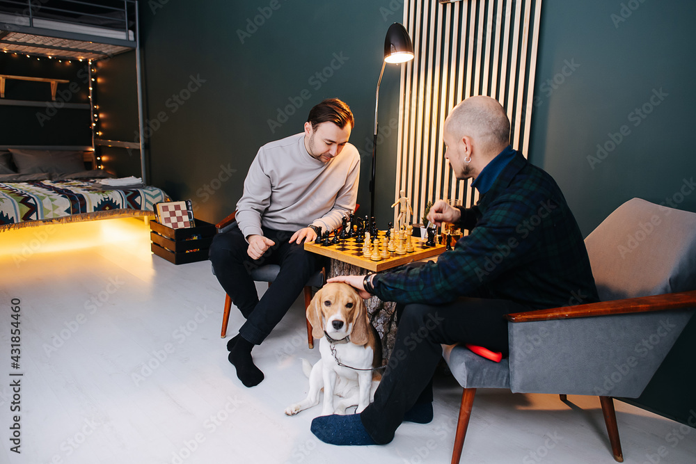 Keen middle aged men playing game of chess at home. One of them playing ...
