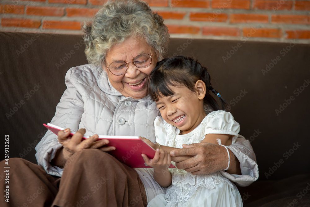 Happy Asia grandmother reading to granddaughter child book at home ...