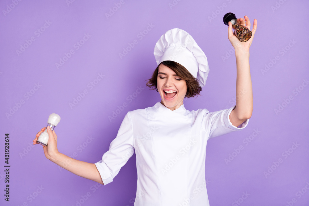 Portrait of attractive funny cheerful chef holding spice bottles ...