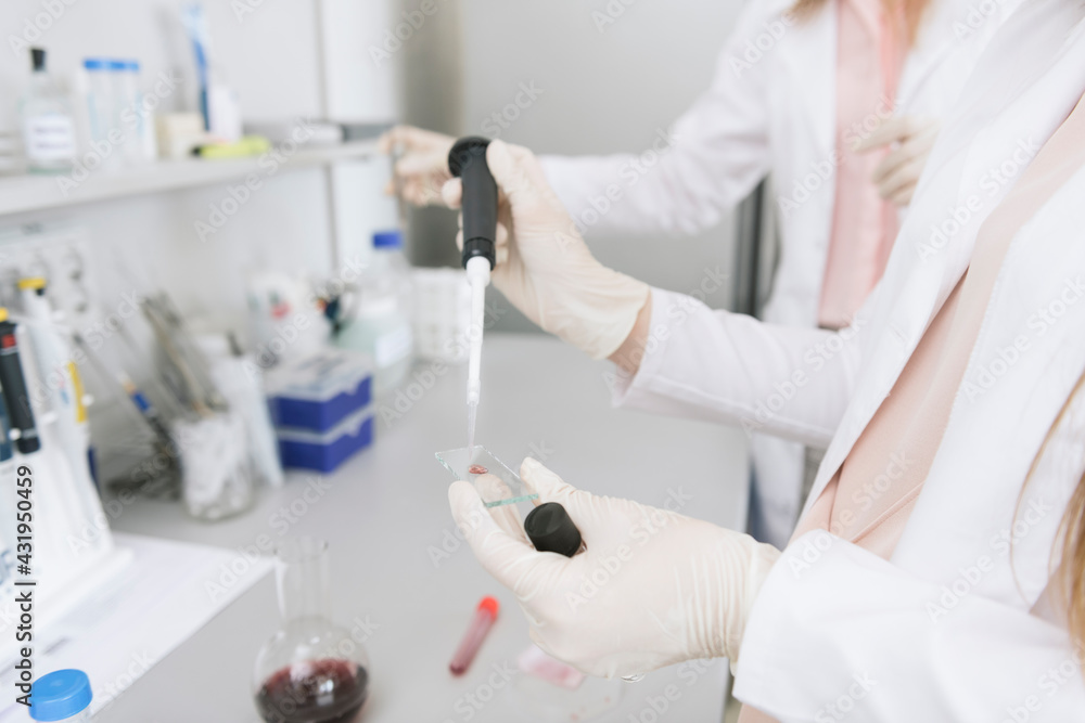 Scientists in white coats preparing sample on microscope slide in lab ...