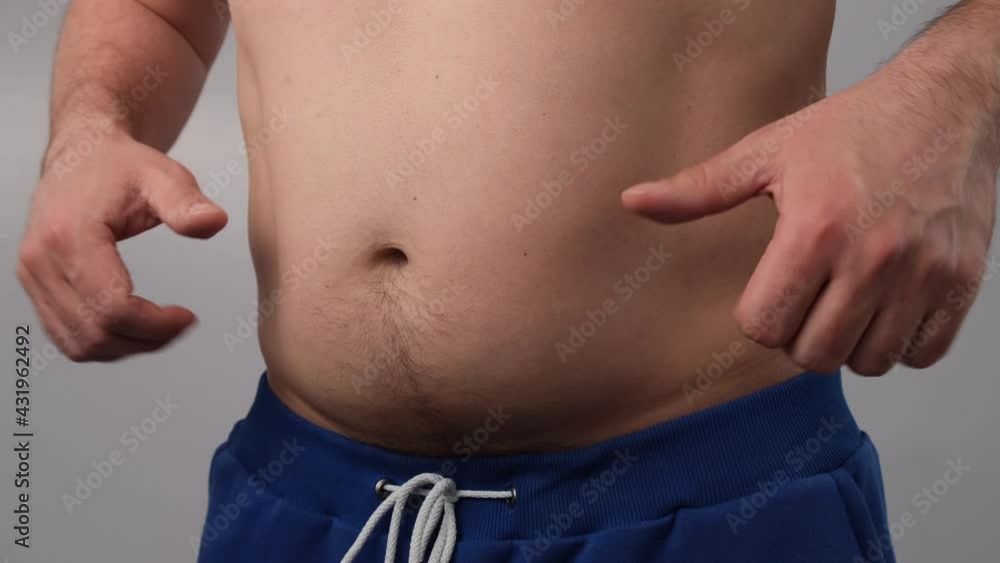 Close-up of a male fat shaking belly against a white background. The ...