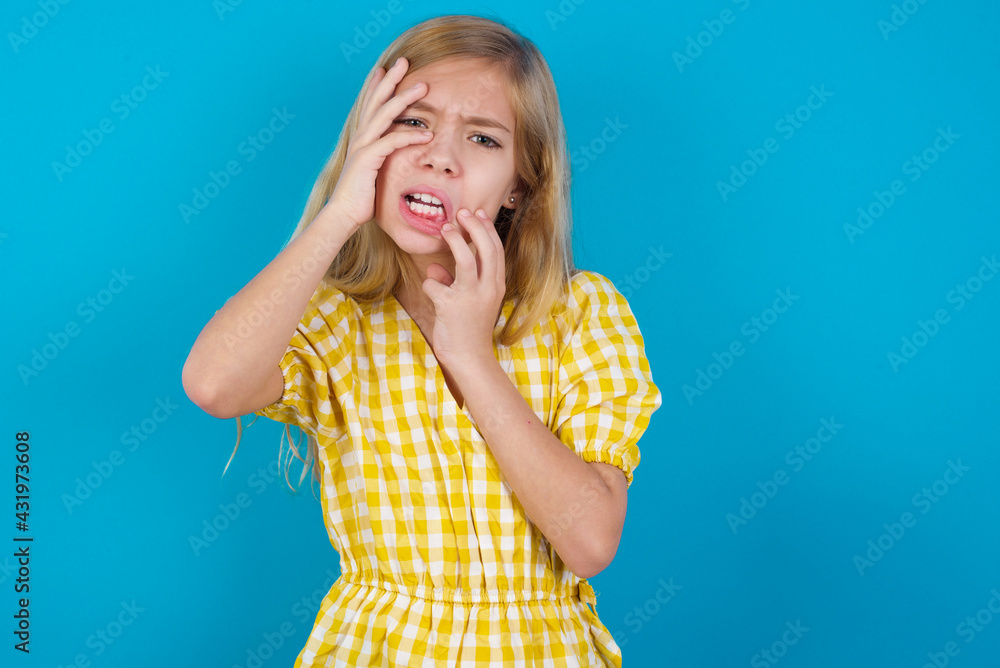 Young gloomy beautiful Caucasian little girl wearing yellow dress over ...