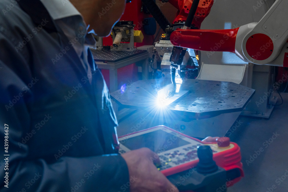 Worker operating control by robotic arm welding in industry Stock Photo ...