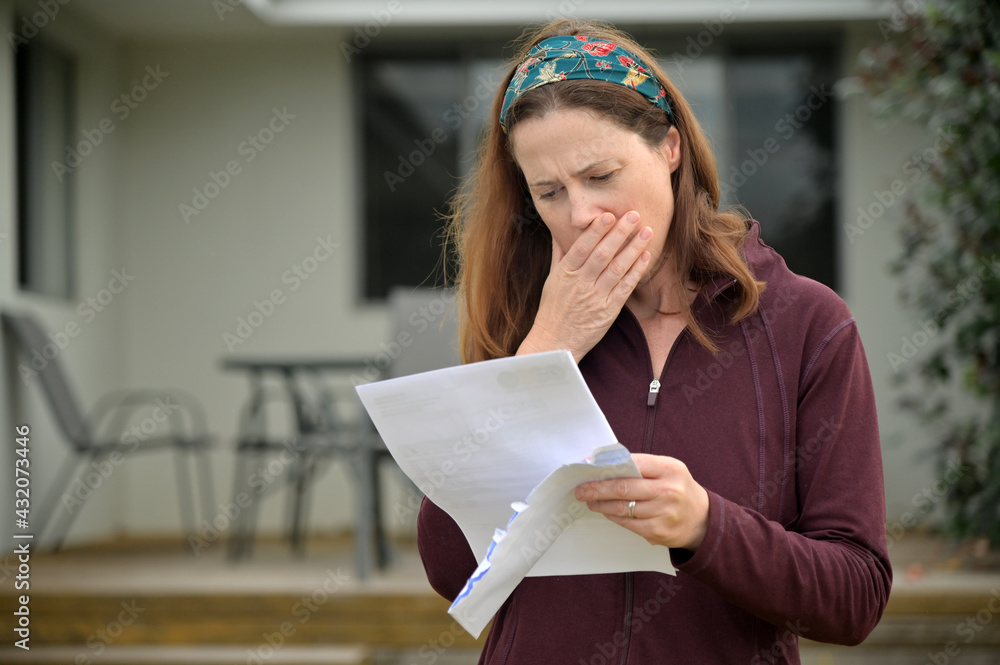 Upset woman reading a letter in home front yard Stock Photo | Adobe Stock
