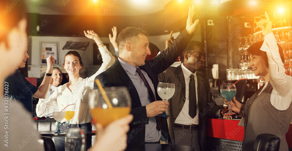 Cheerful businessman with female colleague dancing and drinking alcohol ...