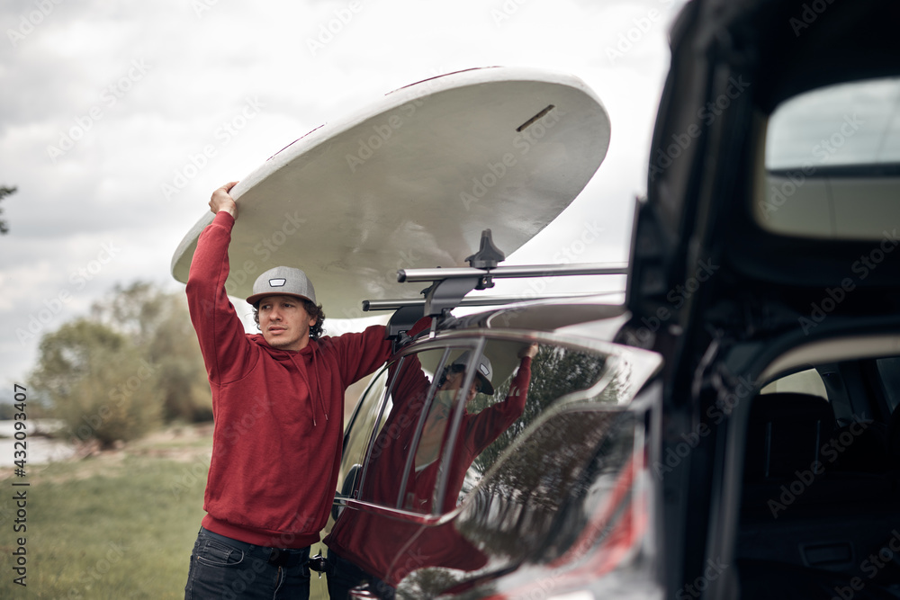 Windsurfer and camper packing and unpacking from a car's roof rack in ...