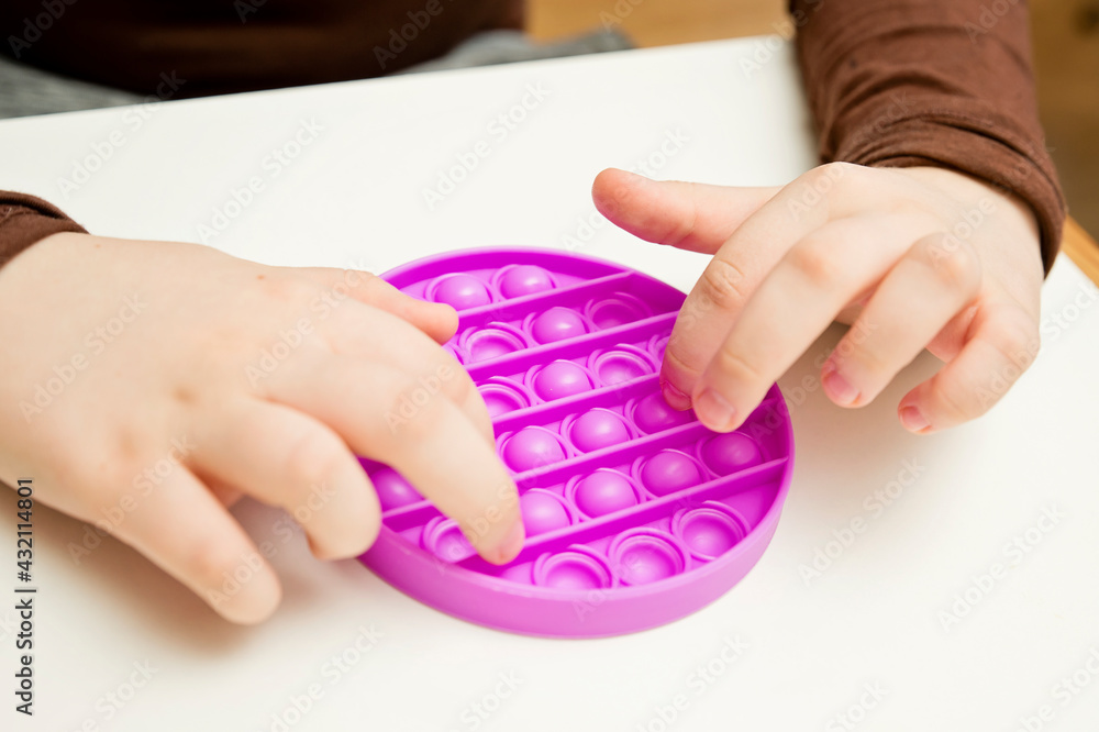 Close up shot of kids fingers on pop it fidget toy. Instrument for ...