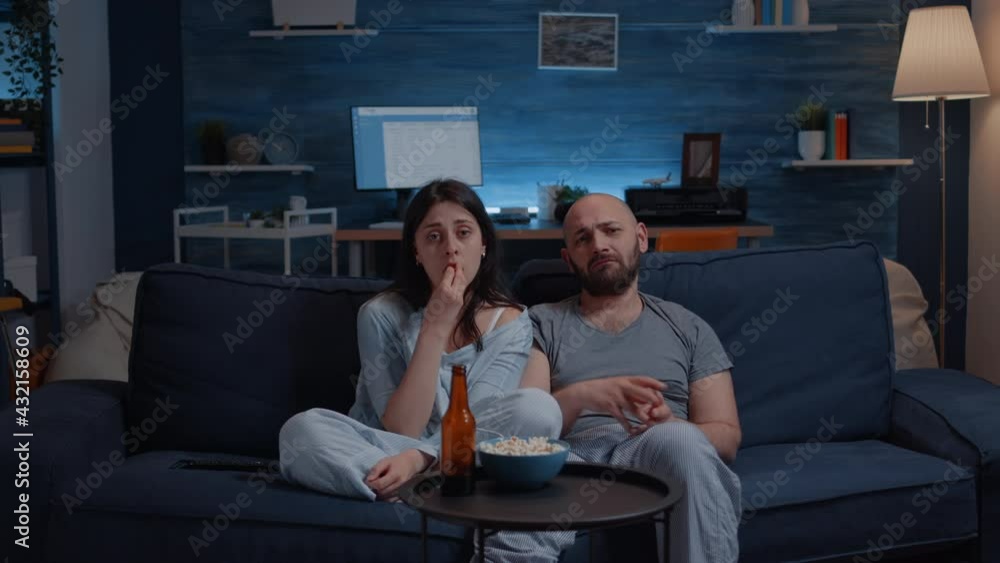 Sensitive couple watching drama movie on tv crying sitting on sofa ...