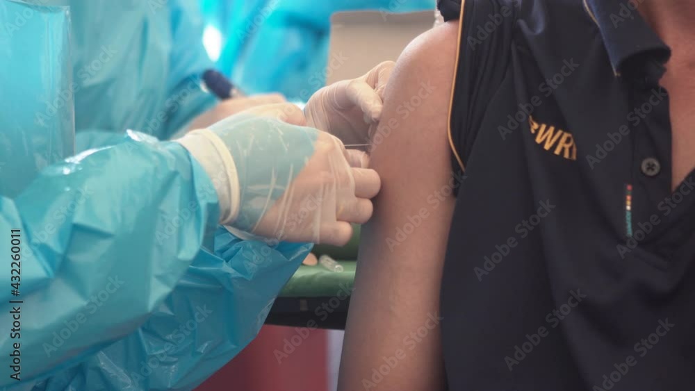 Medical Nurse in Safety Gloves and Protective Mask injects a dose of ...