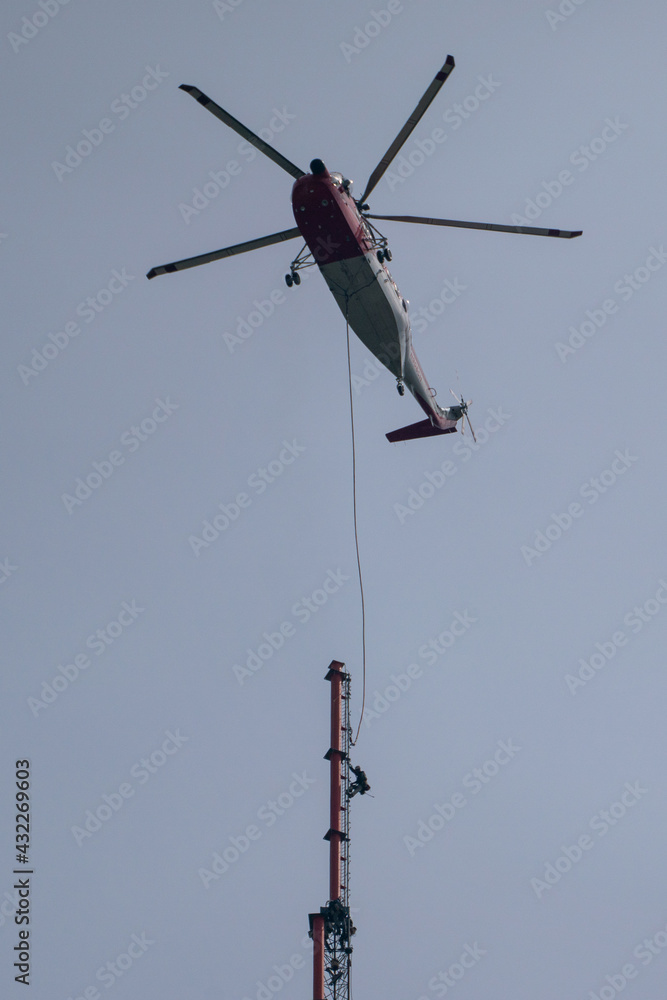 Sky crane helicopter lifting broadcast antenna. Stock Photo | Adobe Stock