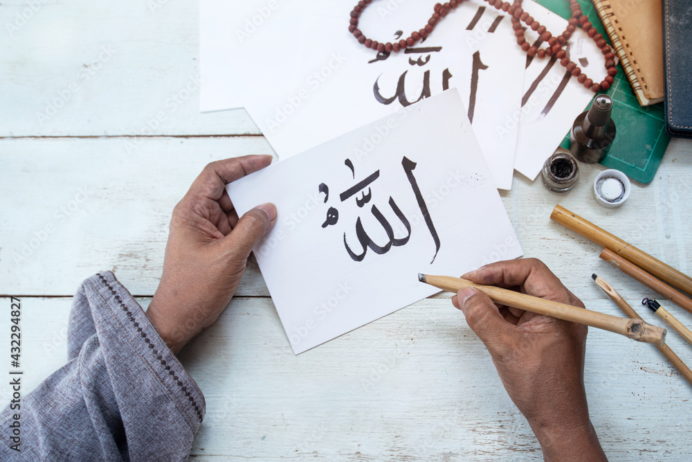Muslim man practicing handwriting Khat with bamboo pen on paper, Arabic ...