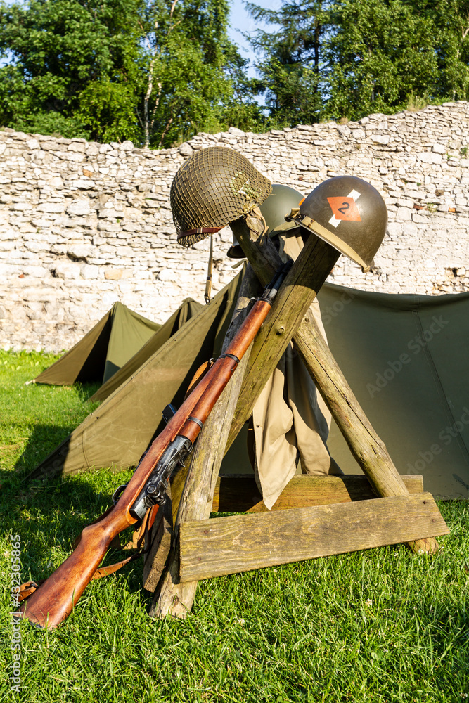 WW2 weapons and helmets laid on display at a re-enactment. American M1 ...