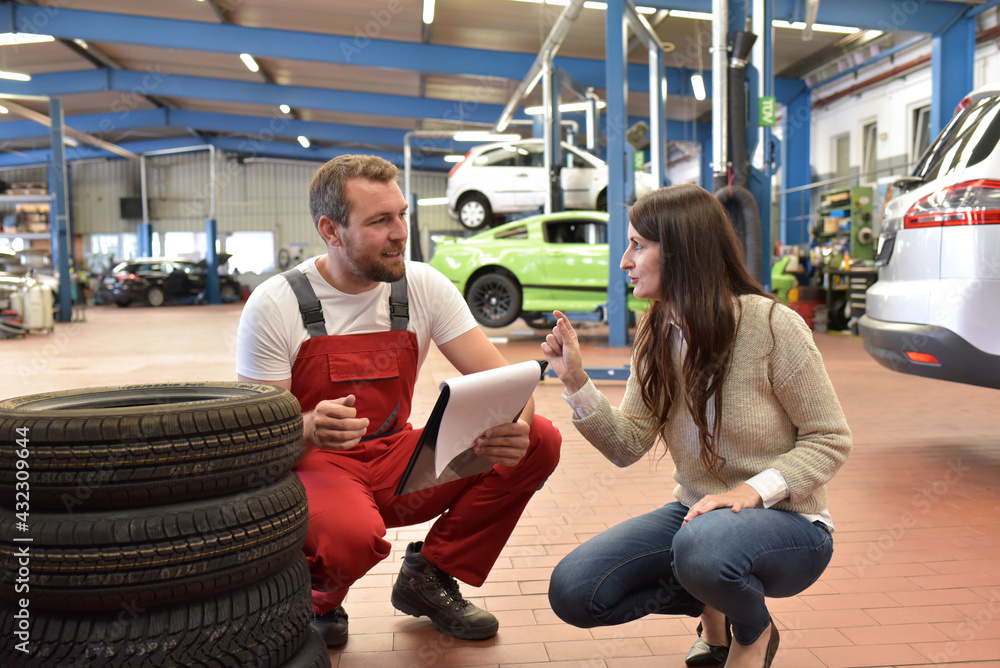 mechanic and customer talking to each other in a garage - changing ...