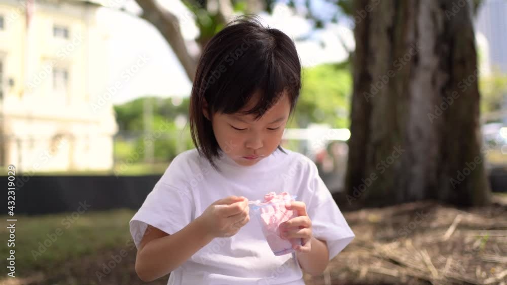 Asian chinese child girl eating ice cream hungrily for the first time ...