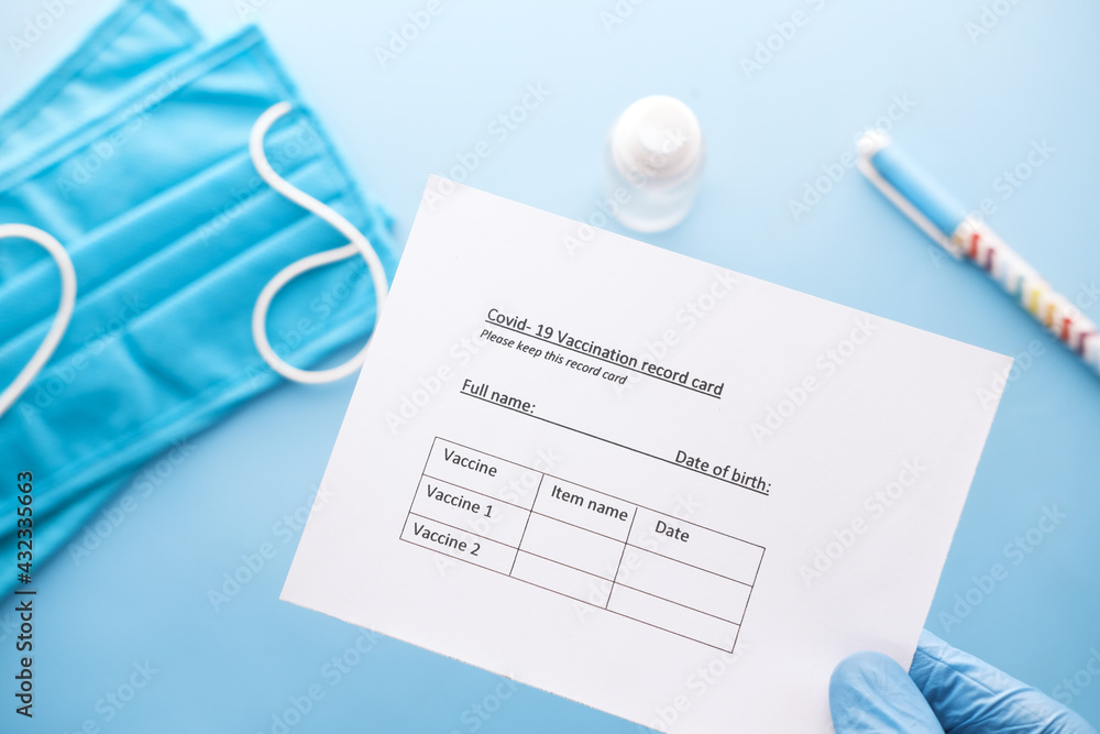 vaccination record card , hand sanitizer and mask on color background ...
