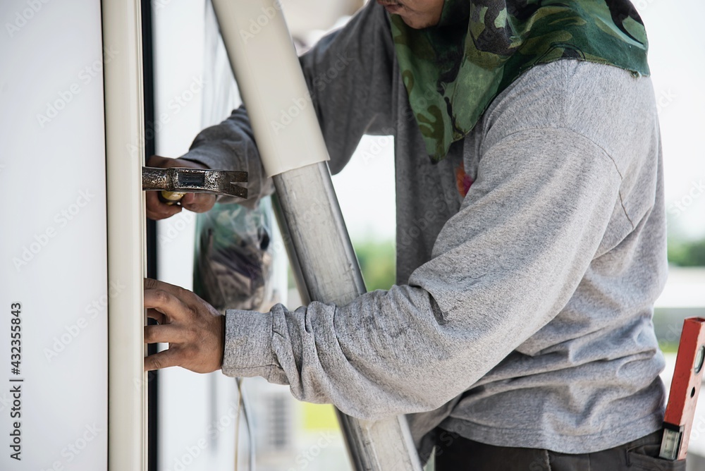 Workman is installing wall compressor pipes using ladder in ...