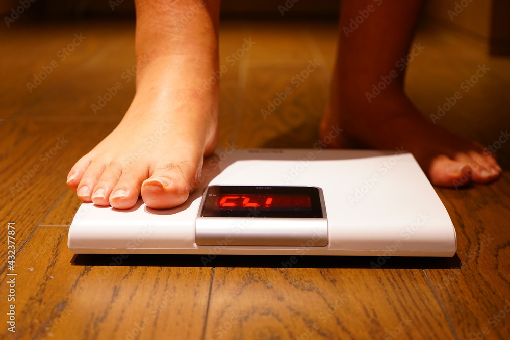 Man measuring her weight using scales on floor - 体重を量る男性 Stock Photo ...