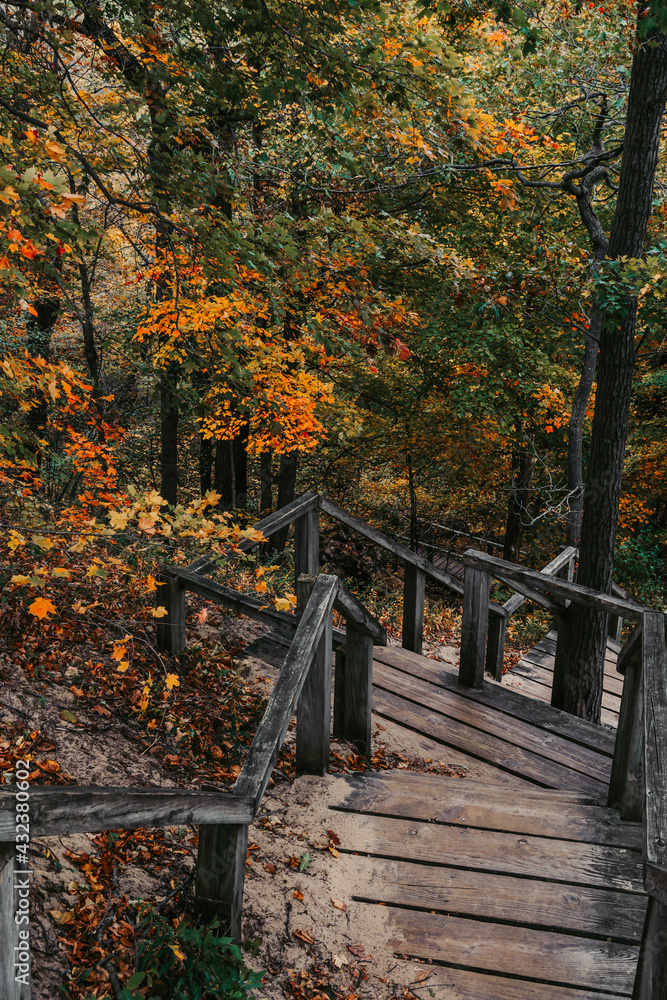 Wooden boardwalk stairs sprinkled with sand lead down into the colorful ...