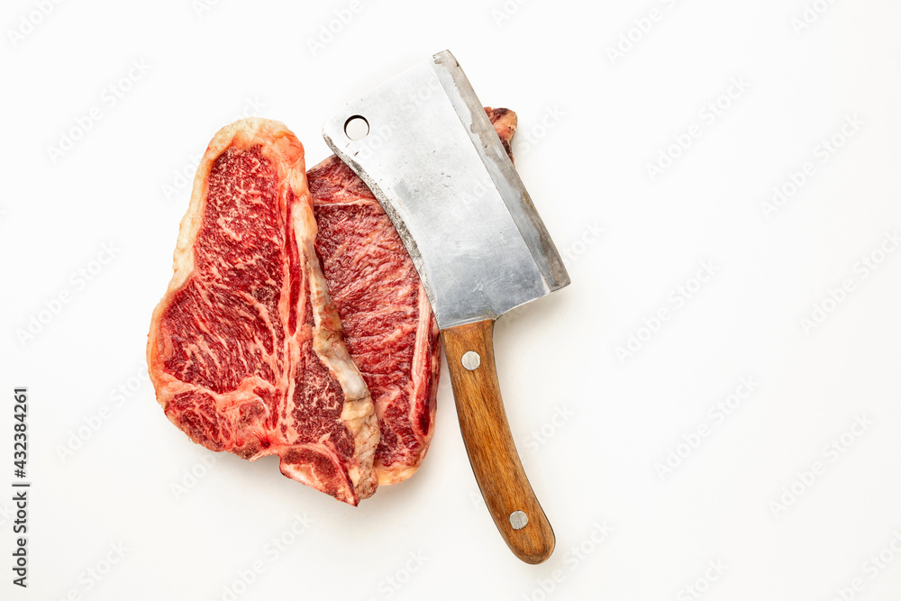 Raw beef steak on the bone with an ax on a white background. Top view ...