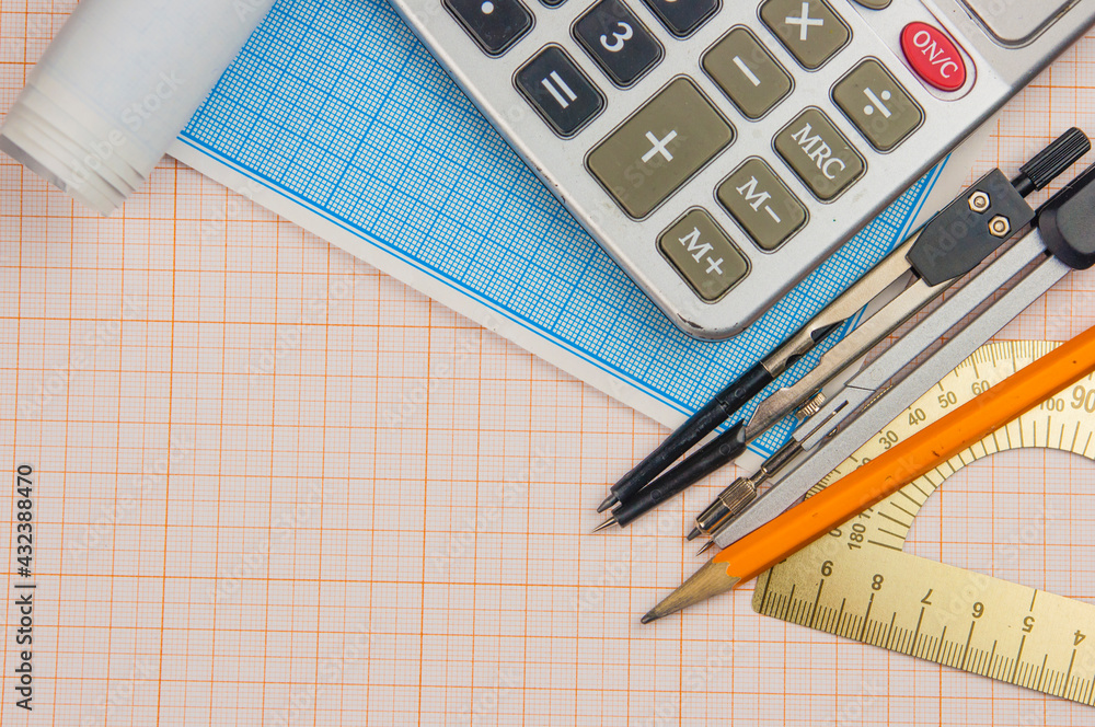 Mathematical instruments over the corner of a math graph paper with ...