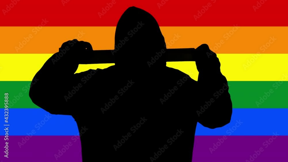 The dark silhouette of a man in a hoodie, over a rainbow LGBT flag ...