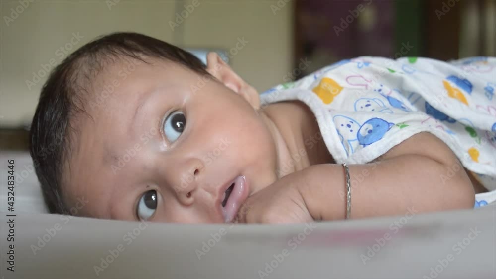 Close up face of cute newborn baby boy looking around while lying on ...
