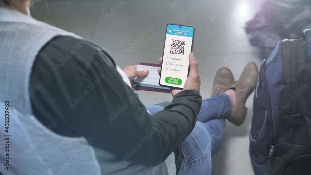 Covid-19 vaccination passport on smart phone screen,woman traveller sits at the airport holding ...