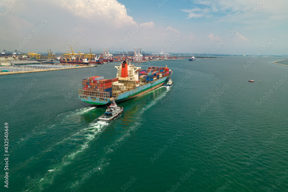 Aerial in front of cargo ship carrying container and running with tug ...