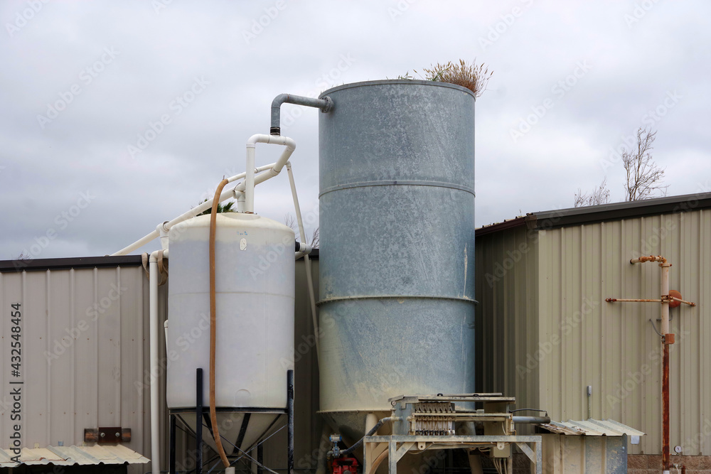 Two silos and warehouse sheds on a sand and gravel open-pit mining site ...