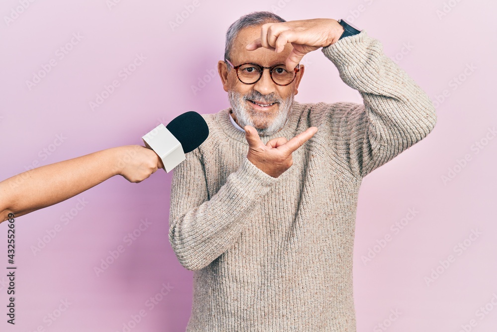 Handsome senior man with beard being interviewed by reporter holding ...