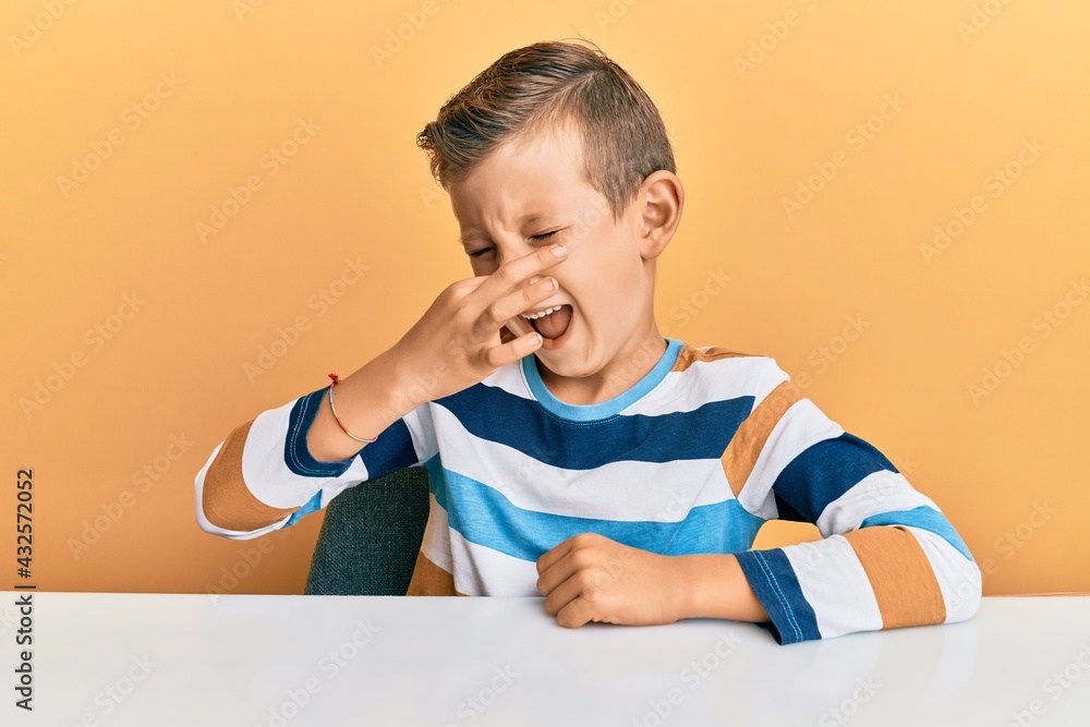 Adorable caucasian kid wearing casual clothes sitting on the table ...