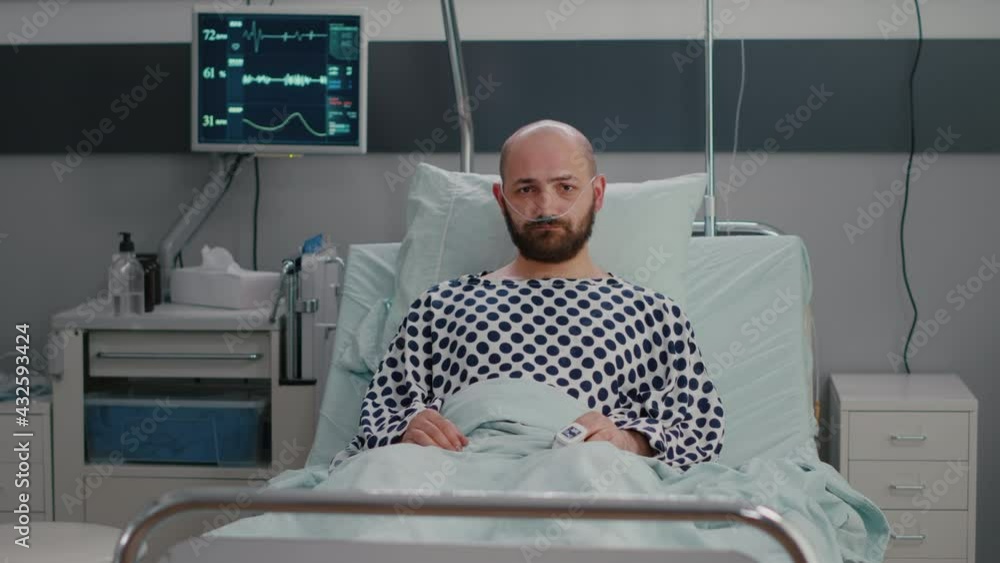 Potrait of sad sick man wearing nasal oxygen tube lying in bad looking ...