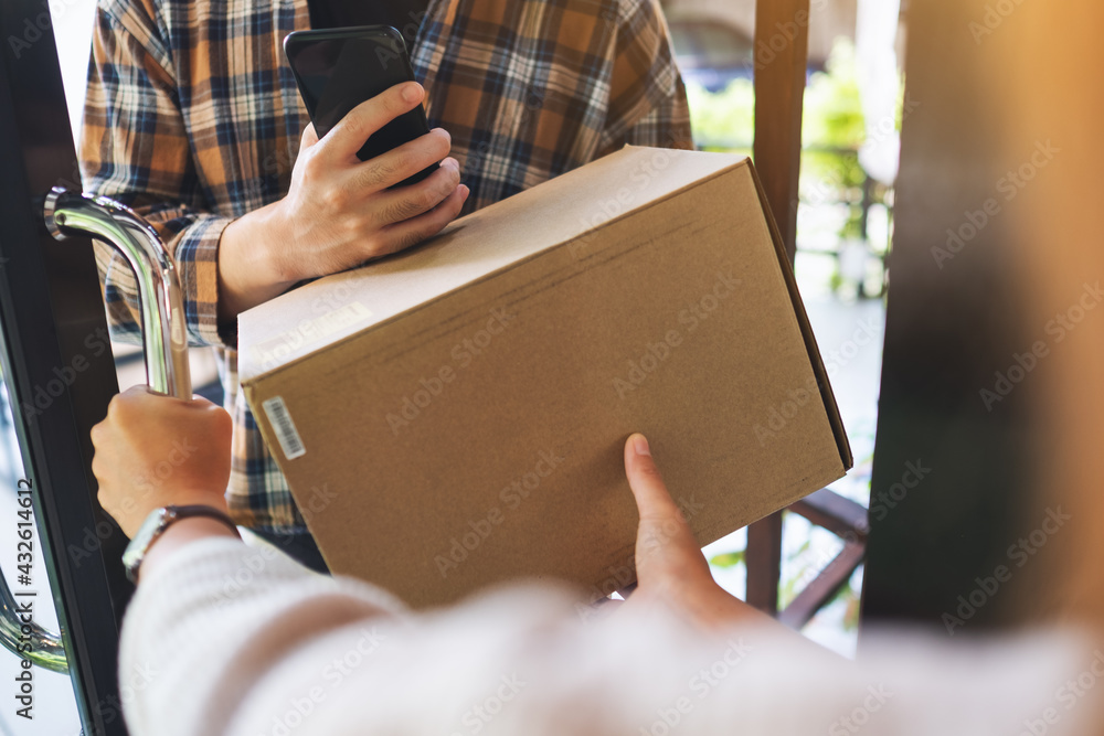 Closeup image of a woman receiving parcel box from delivery man at the ...